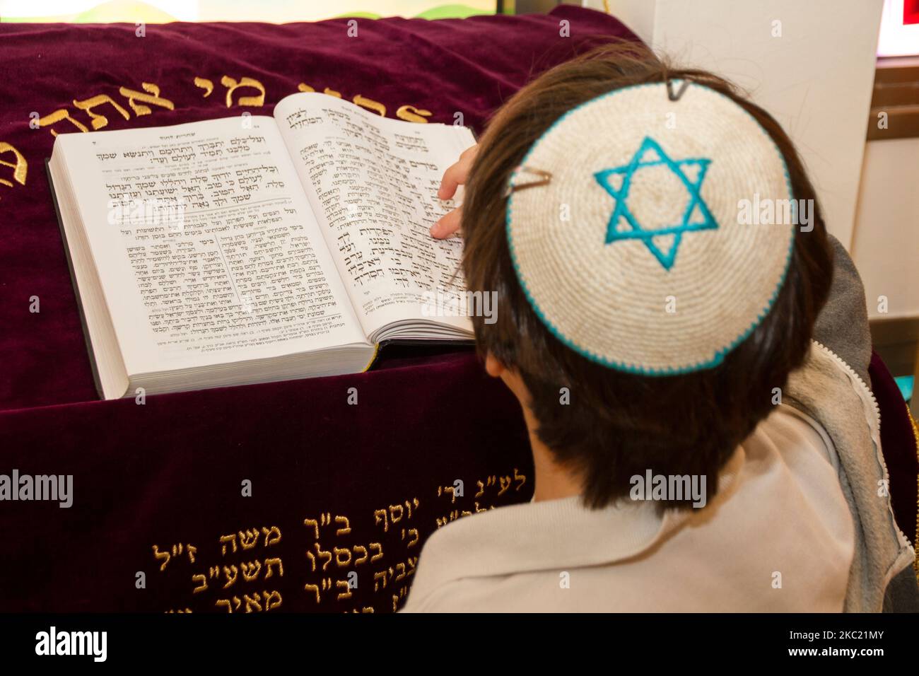 A rear view of praying young man pointing at a phrase in a bible book ...