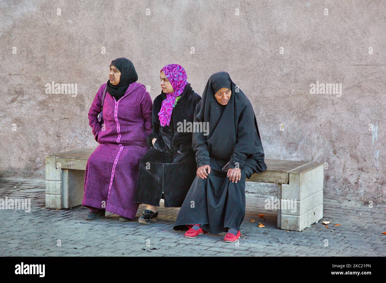 Women sit on a bench in the main square of the city of Meknes, Morocco ...