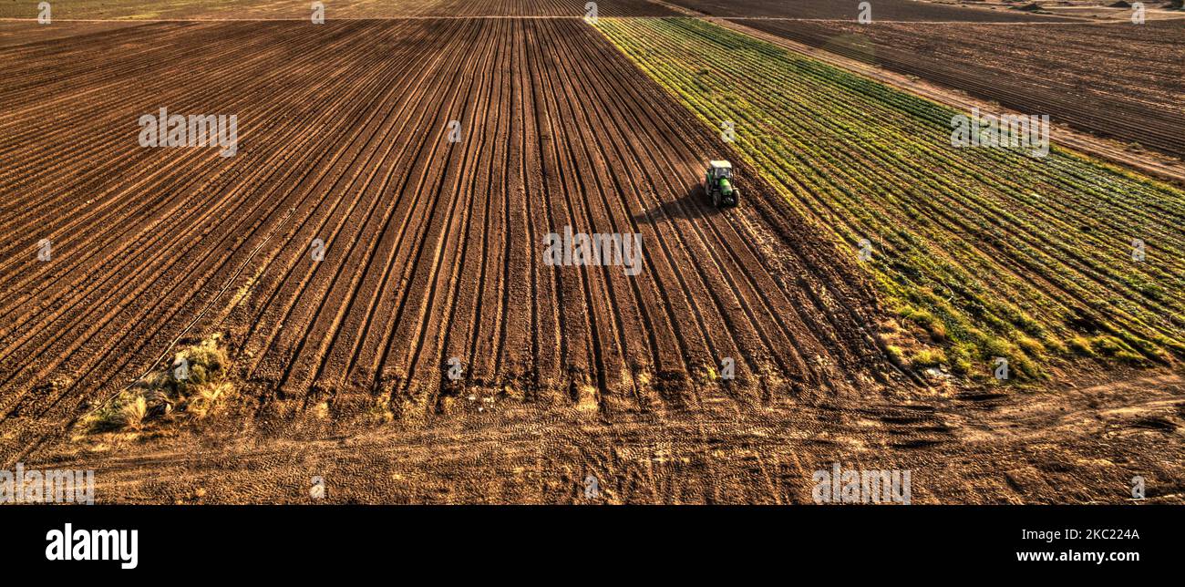 Aerial view of tractor cultivating and harrowing field at spring season ...
