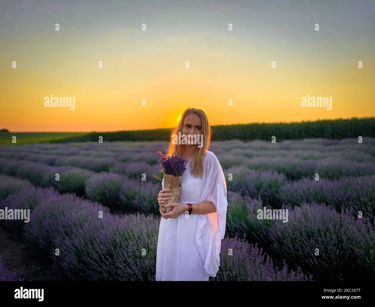 A beautiful young blonde happy Caucasian woman wearing a white dress in ...