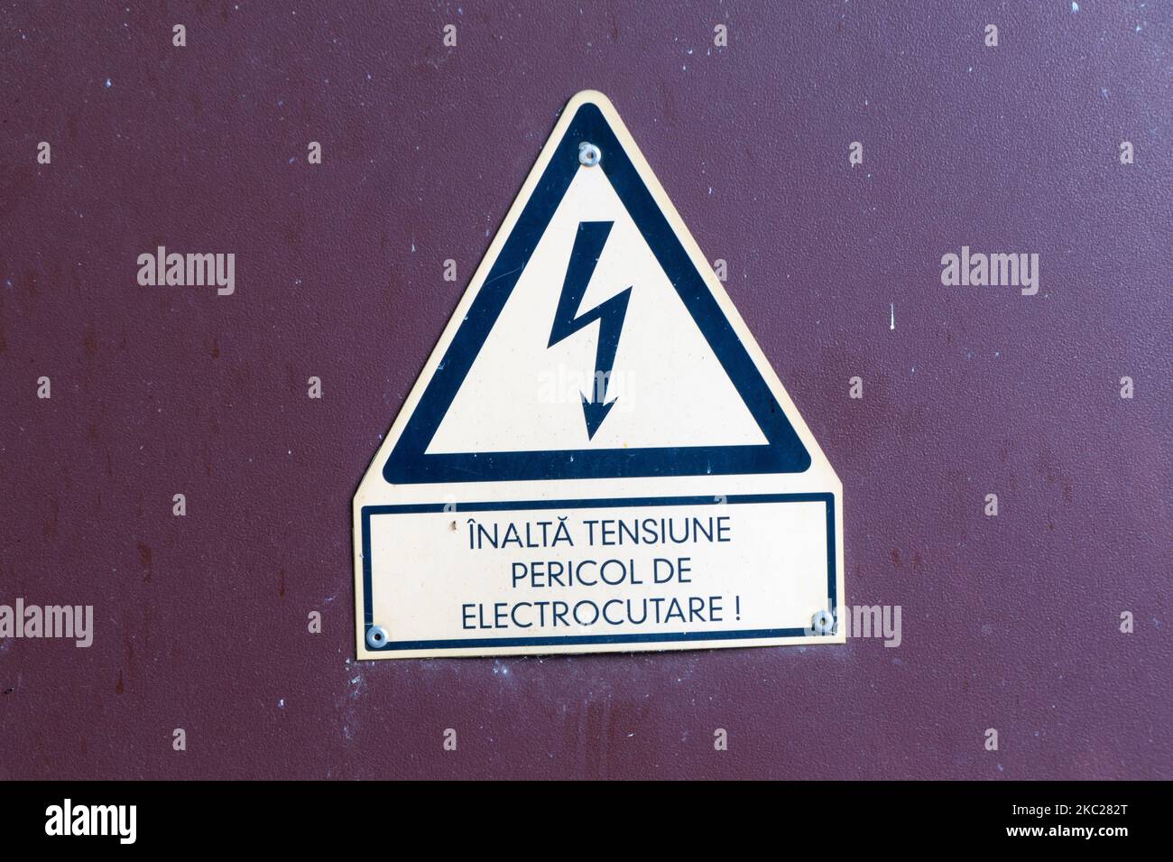 A closeup of a Romanian sign for high voltage on a purple background ...