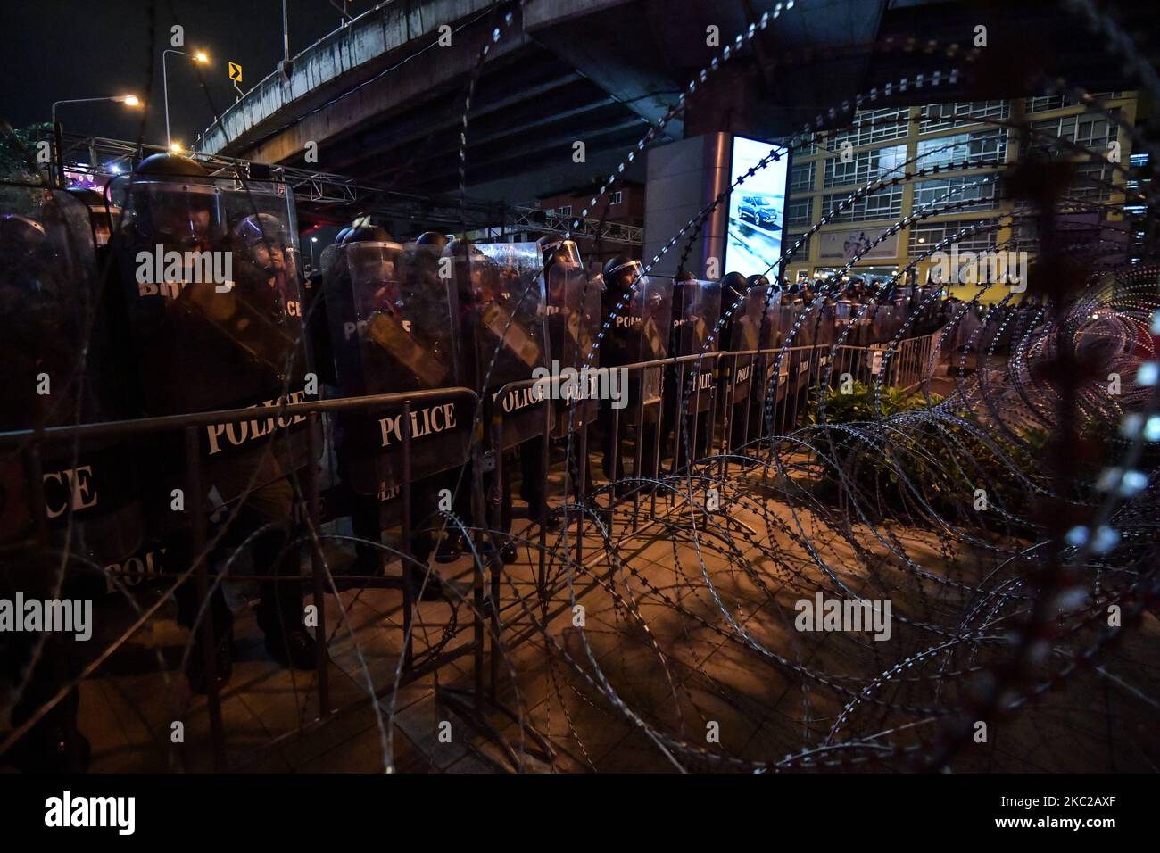Riot police stand guard behind a barricade of barbed wire during a ...