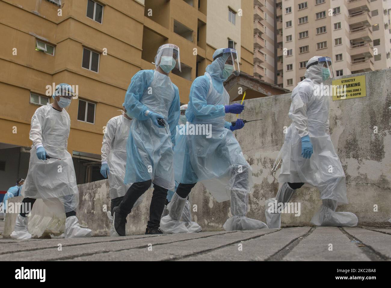 Medical workers wearing personal protective equipment (PPE) walk at the ...