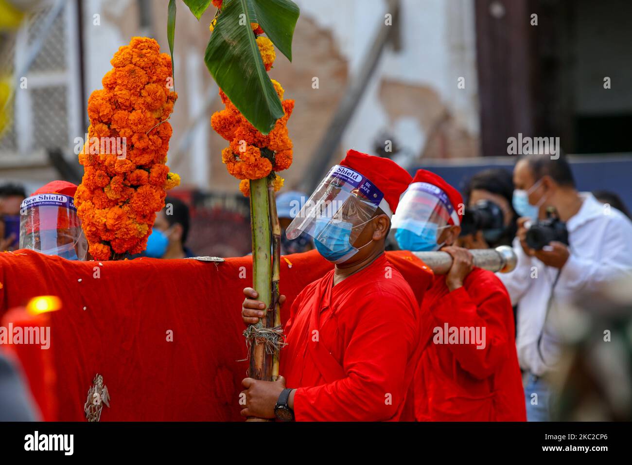 Nepali Hindu devotees wearing face shield and facial mask carry plants ...