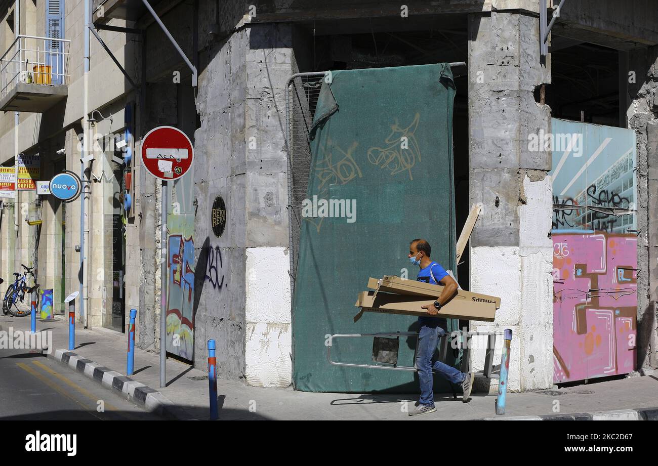 A man wearing a protective mask carries a staircase on a shopping ...