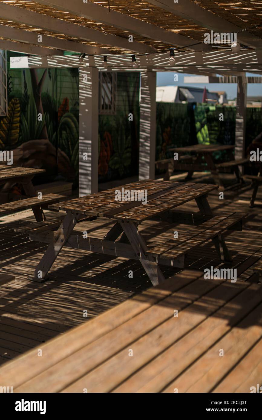 The vertical view of an outdoor cafeteria wooden bench and tables under ...