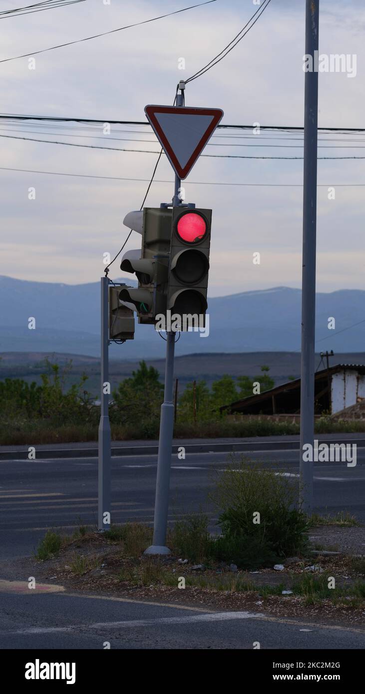 A vertical shot of a traffic light showing a red light in a city with ...