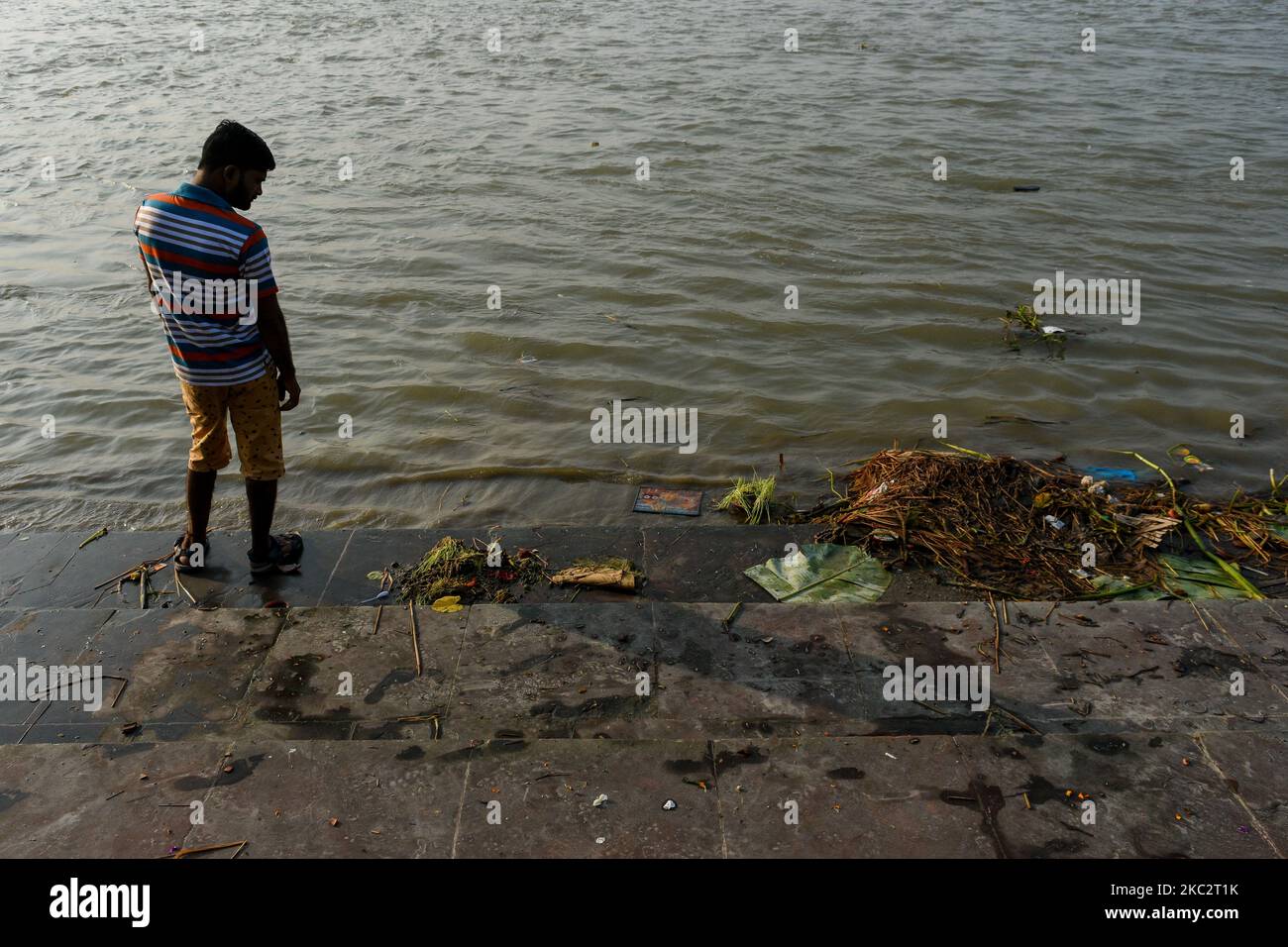 A man observes a pile of garbage that rests at the river bank of Ganges ...