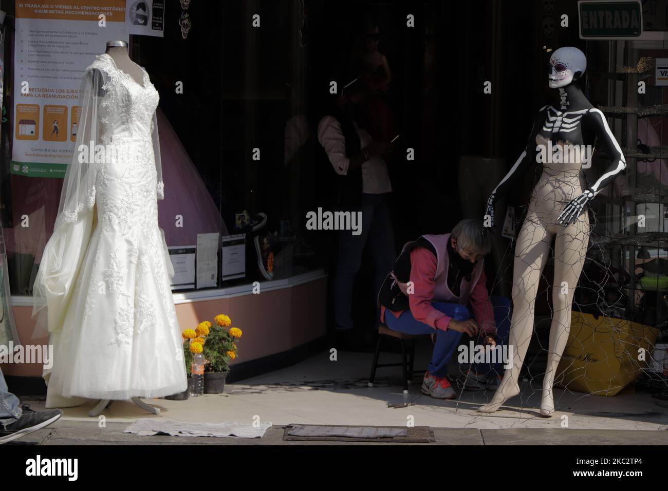 A woman fixes a catrina-painted mannequin outside the La Lagunilla ...
