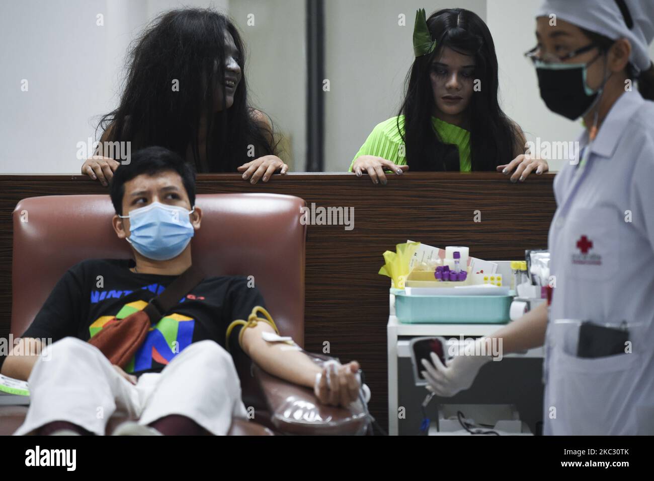 A Thai blood donor donate their blood as a staff member dressed in a ...