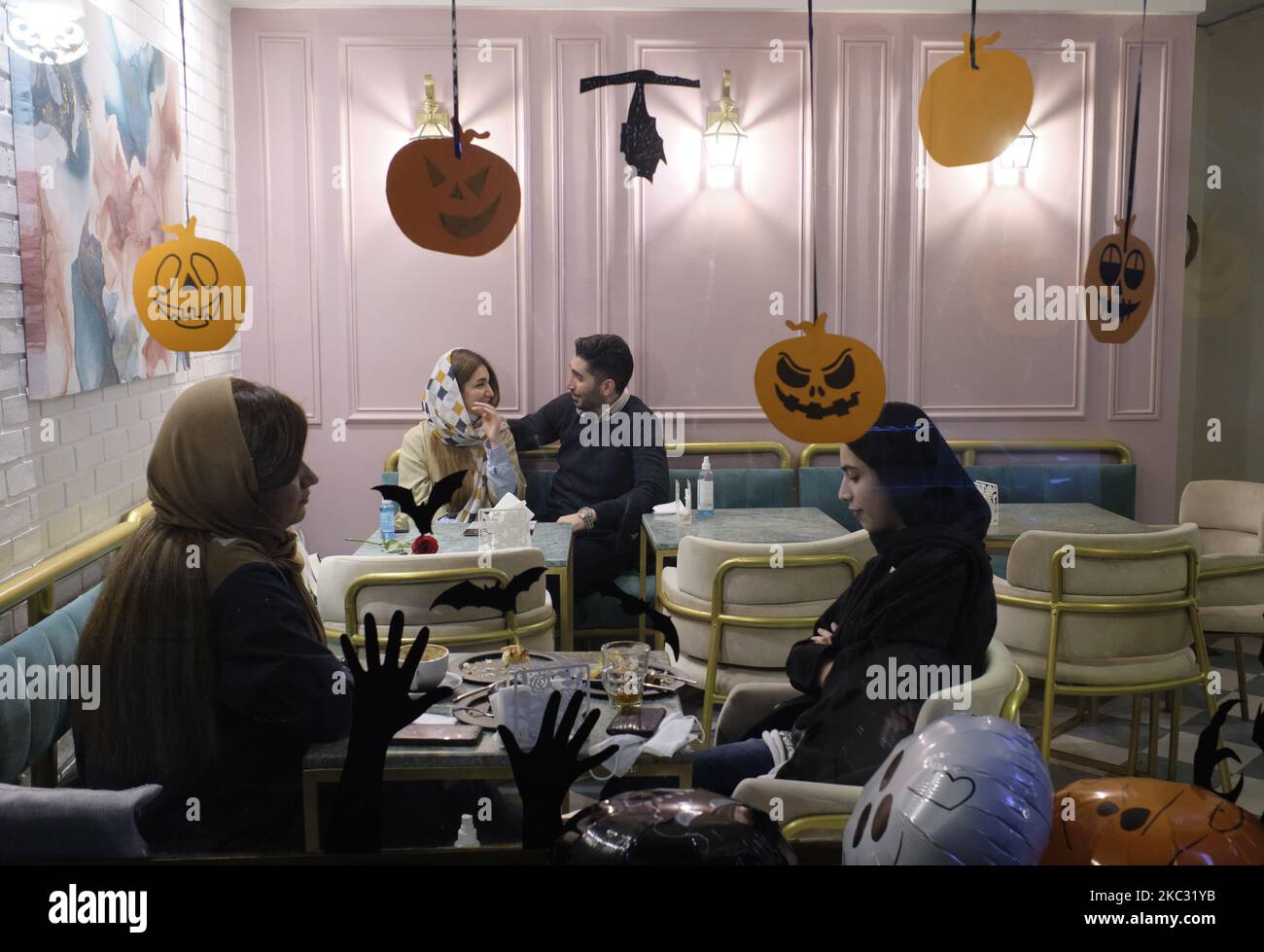 Iranian youth sit in a cafe that is decorated for Halloween ...