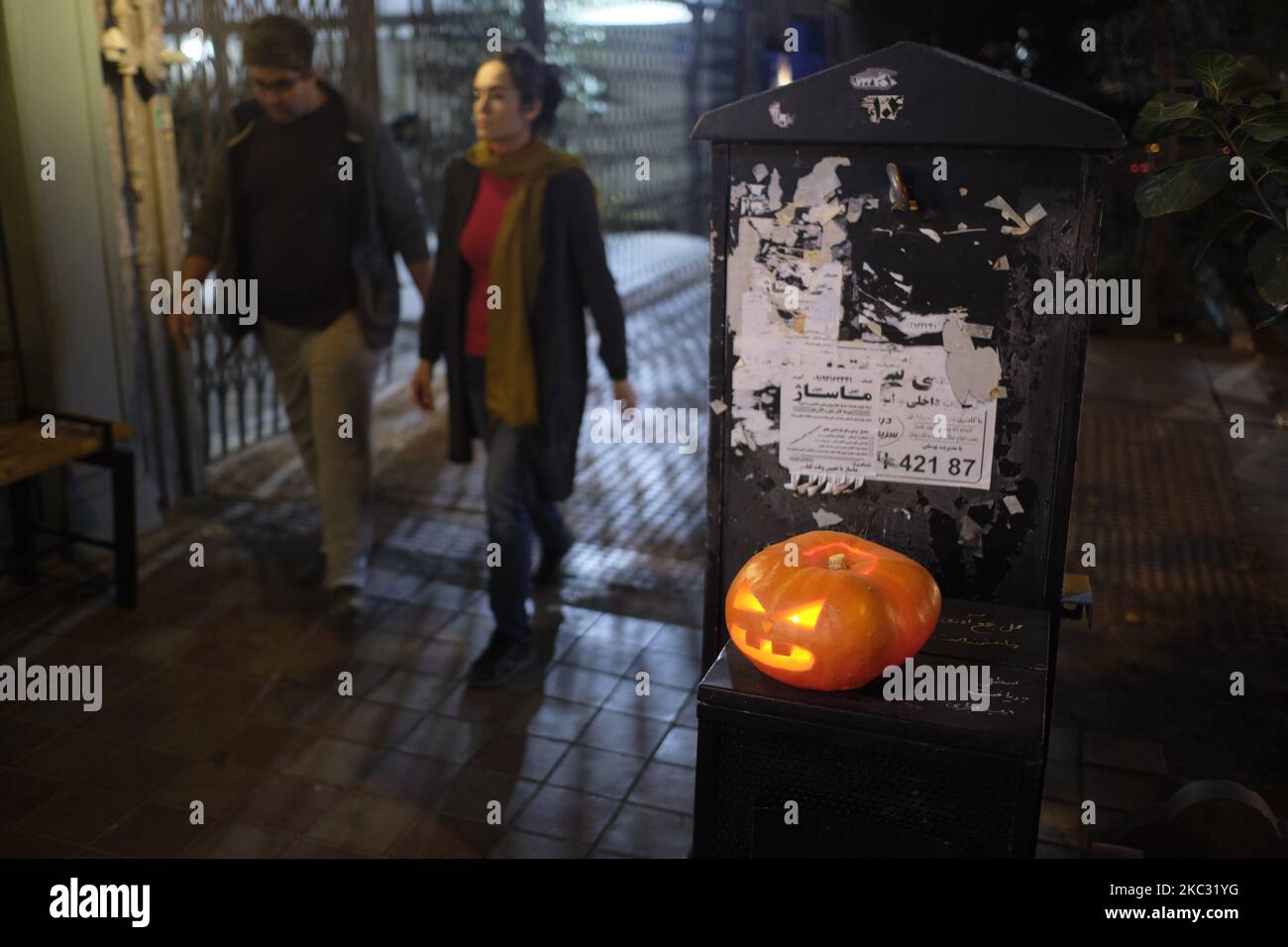 An Iranian couple walk past a pumpkin which is decorated for Halloween ...