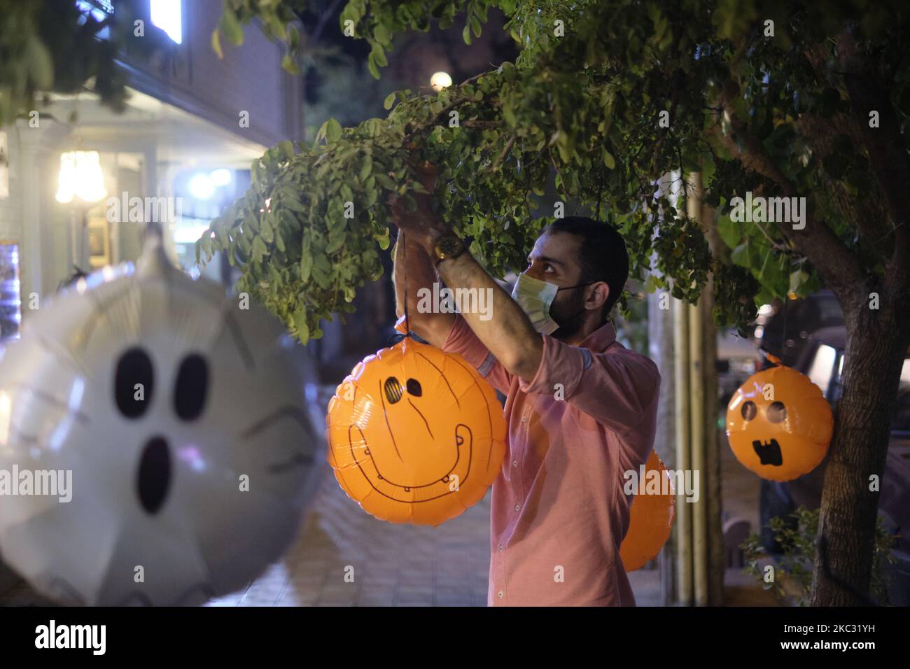 An Iranian employee of a cafe wearing a protective face mask hangs a ...