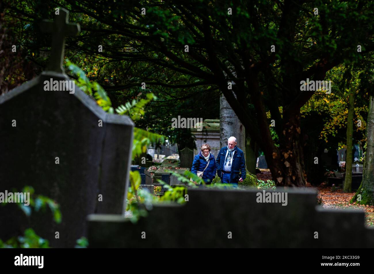 A couple is standing up in front of a family grave during the ...