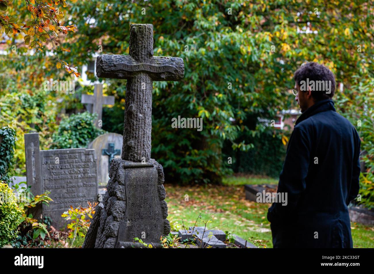 A man is standing up in front of a family grave during the celebration ...