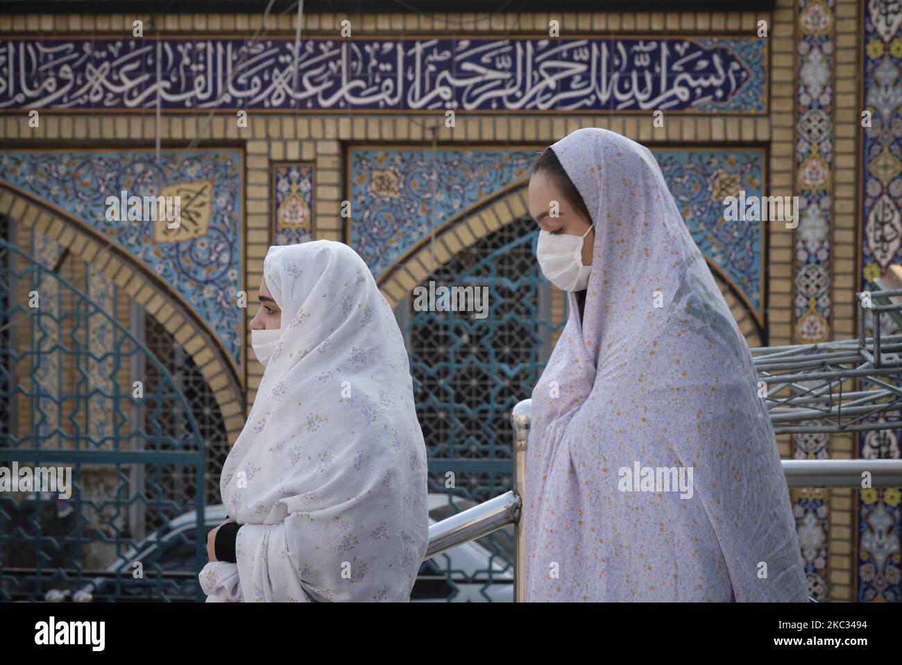 Two Iranian veiled women wearing protective face masks pray as they ...