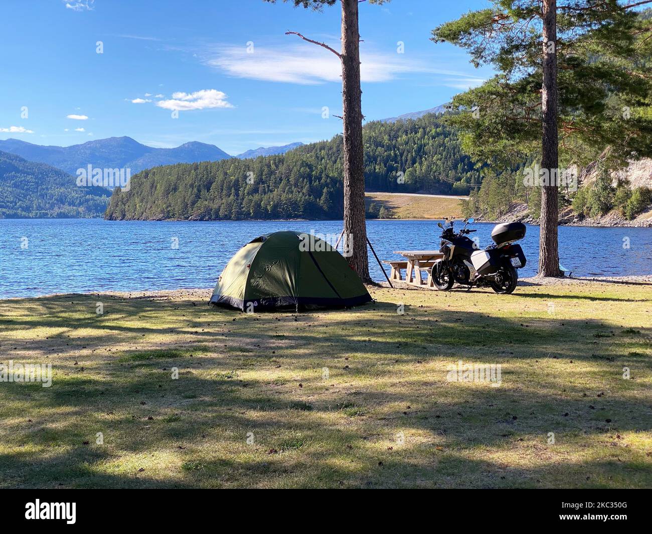 A beautiful view of a tranquil lake near a campground with a green tent ...