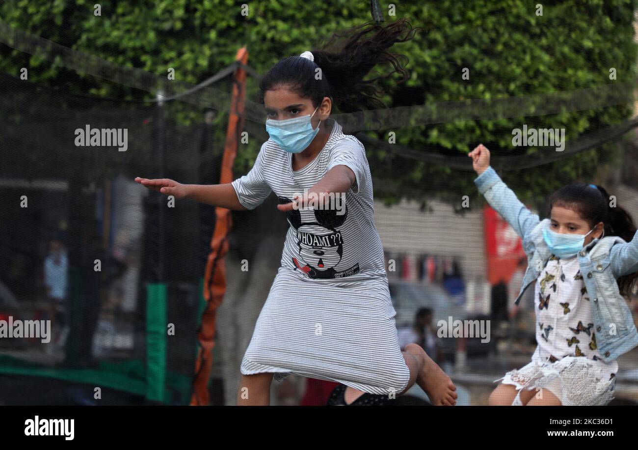 Palestinian children wearing a face mask, play in a public park, in ...