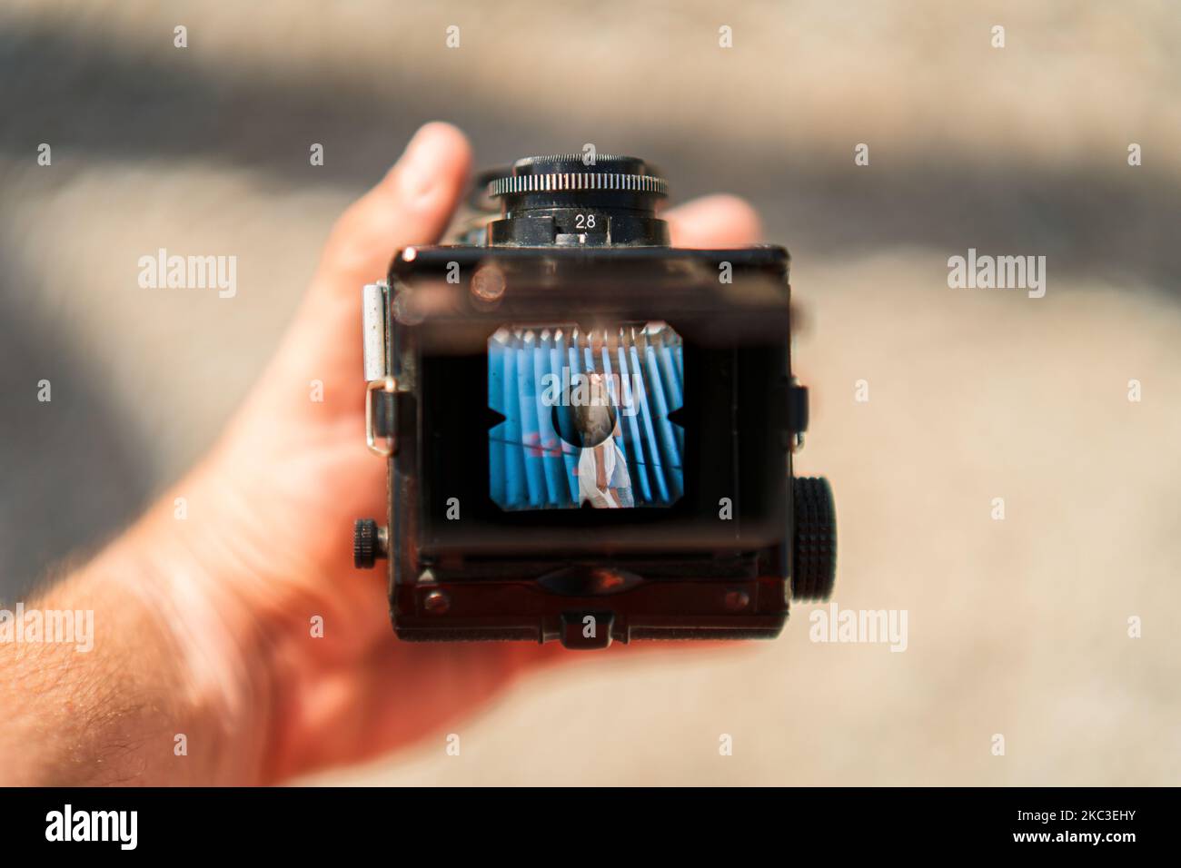 A hand holds a twin-lens reflex camera with a girl's picture displayed ...