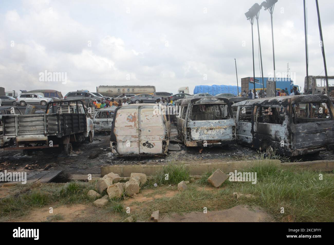 People stand next to burned cars after a tanker exploded on Lagos ...