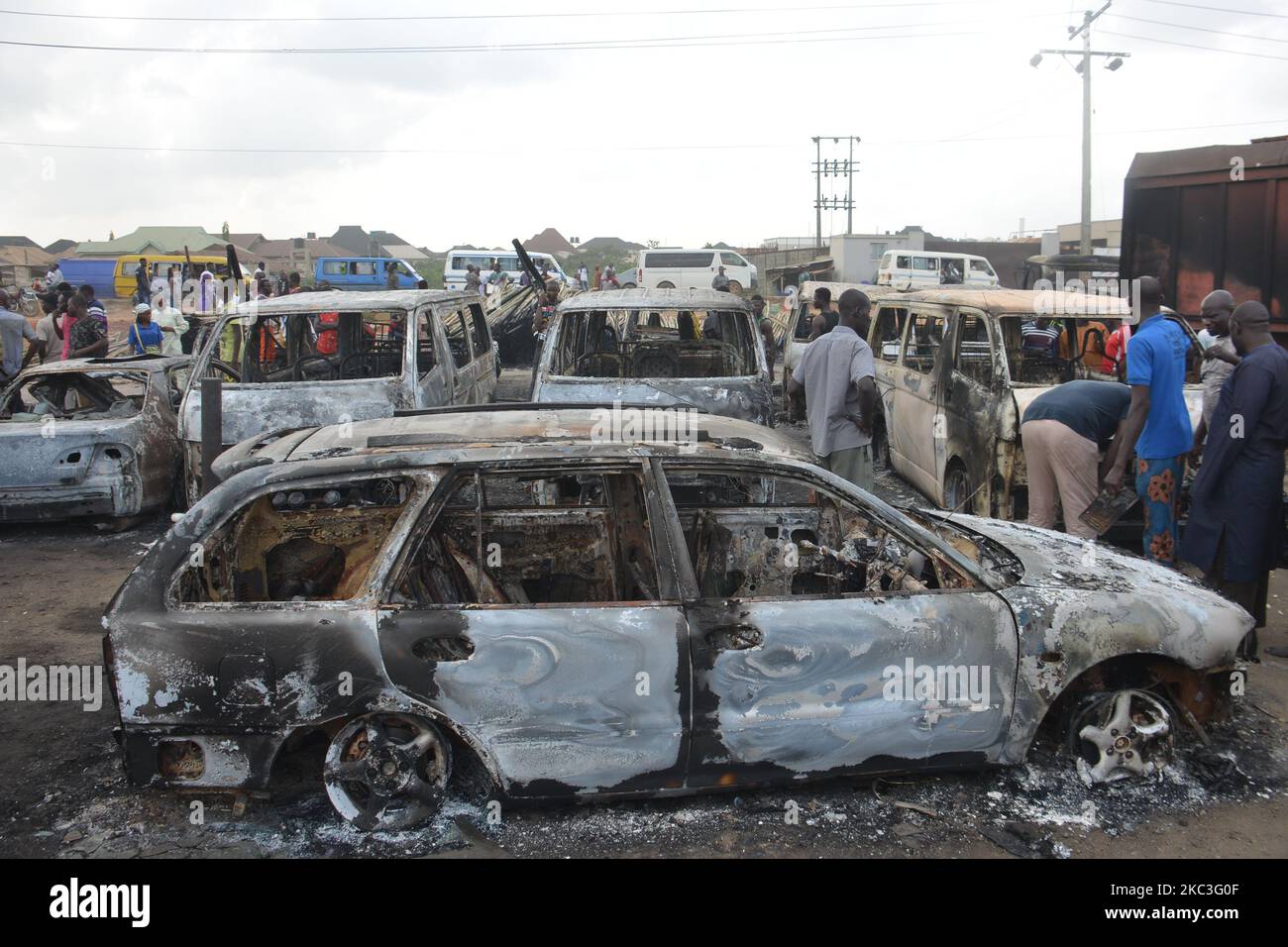 People stand next to burned cars after a tanker exploded on Lagos ...