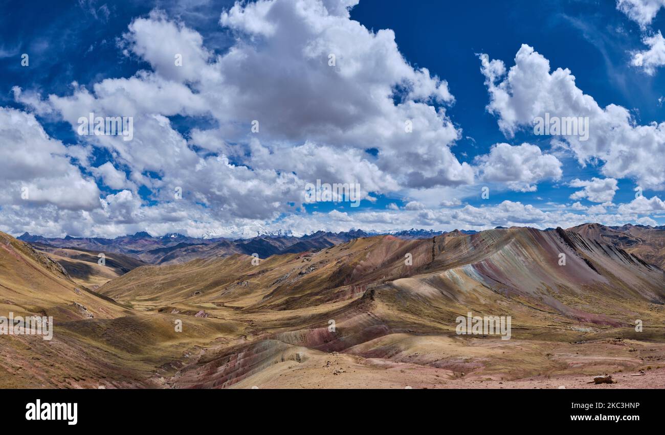 A scenic shot of the Rainbow Mountain under a blue sky with clouds in ...