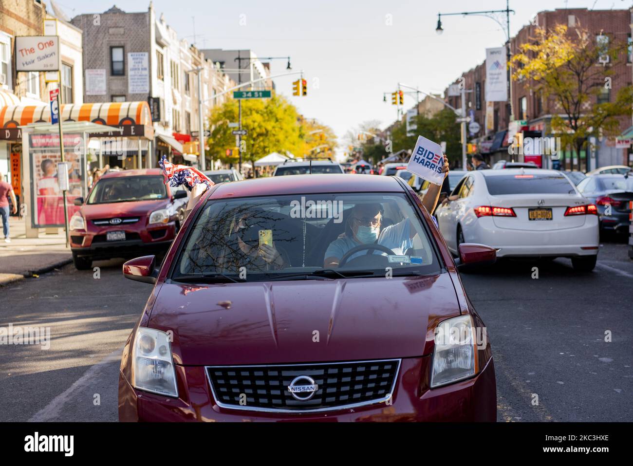 Passengers hold a Biden Harris sign out their car window during a ...