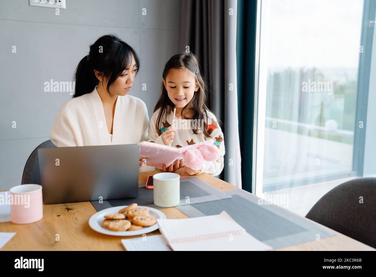 Asian girl doing homework with her mother in kitchen at home Stock Photo - Alamy