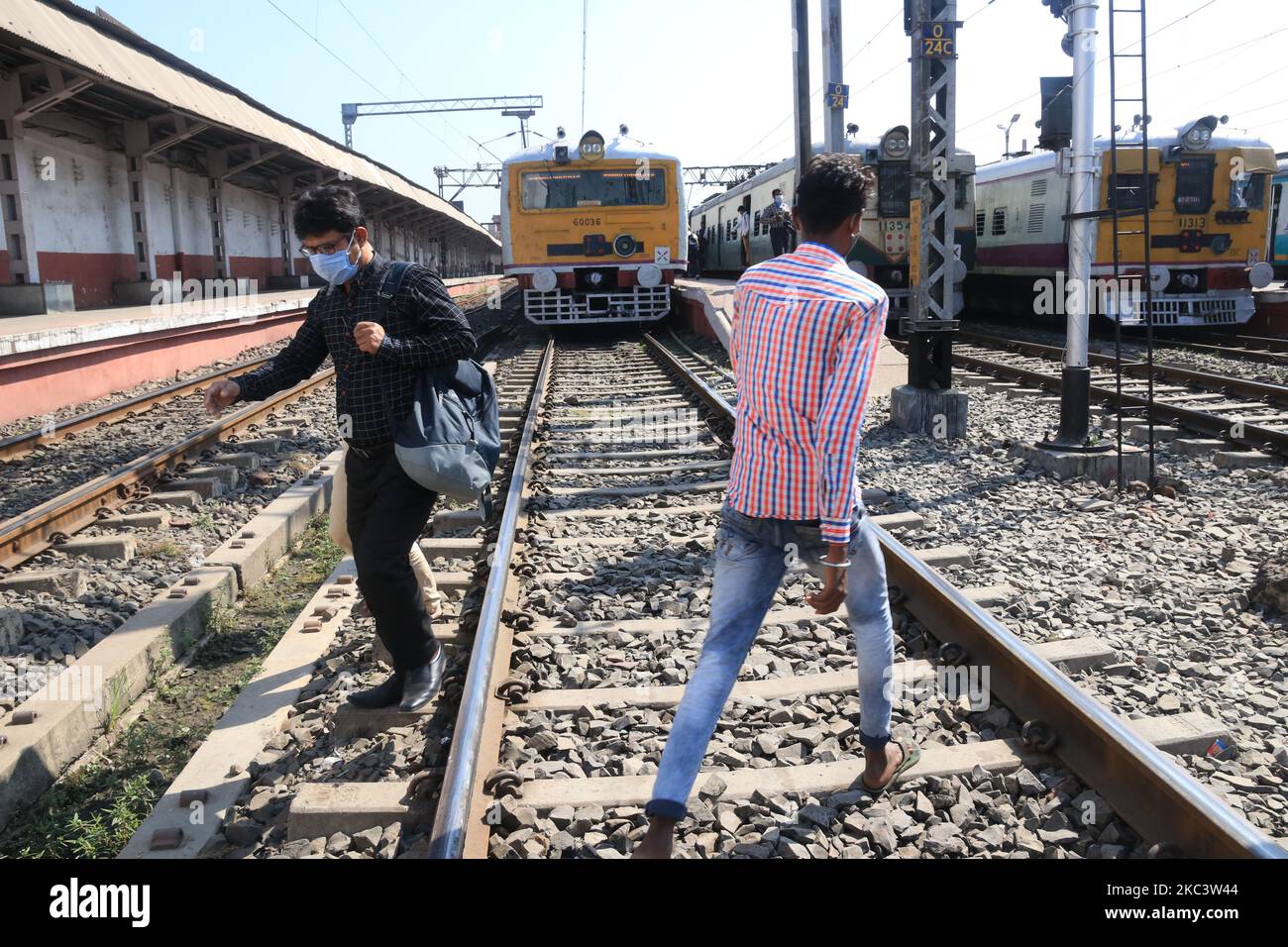 Passengers walk railway track after coming out a Local Train at Howrah ...