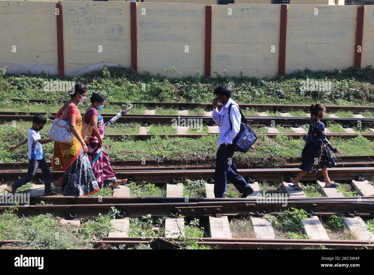 Passengers walk railway track after coming out a Local Train at Howrah ...