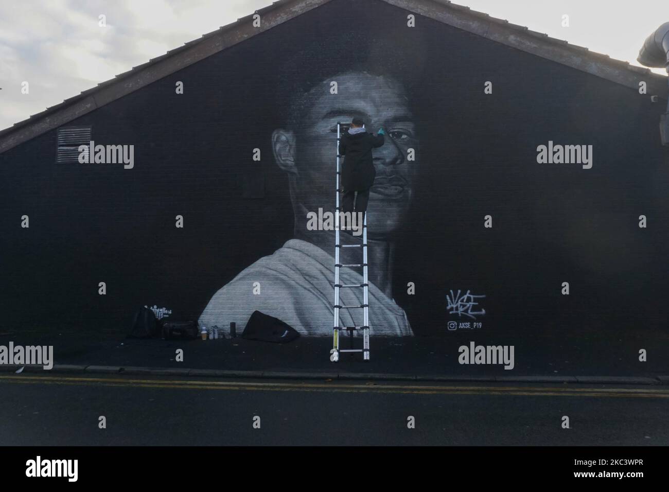 Street artist, AKSE, puts the finishing touches to his mural of ...