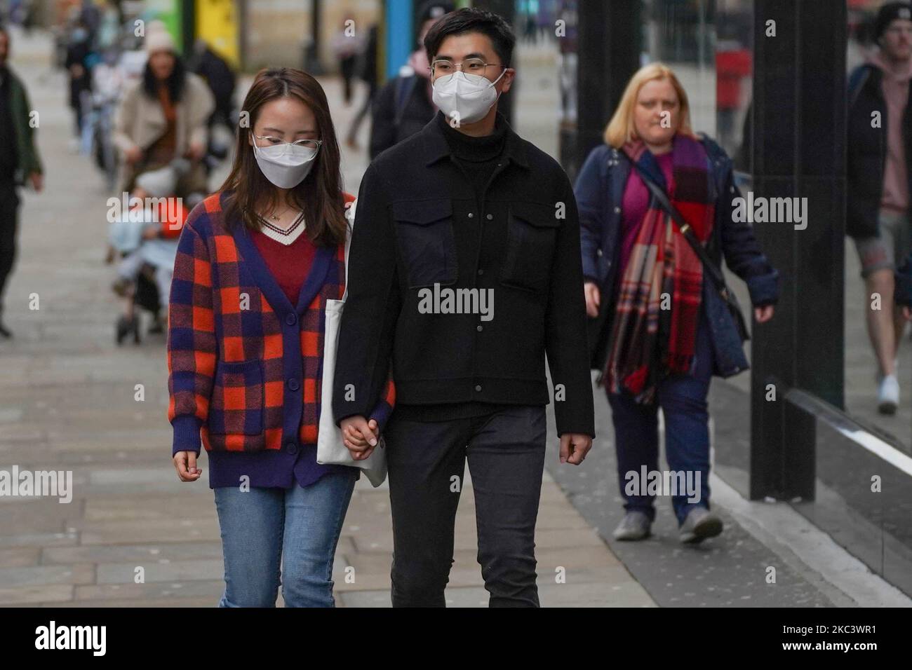 Shoppers wearing face a covering walk through the streets of Manchester ...