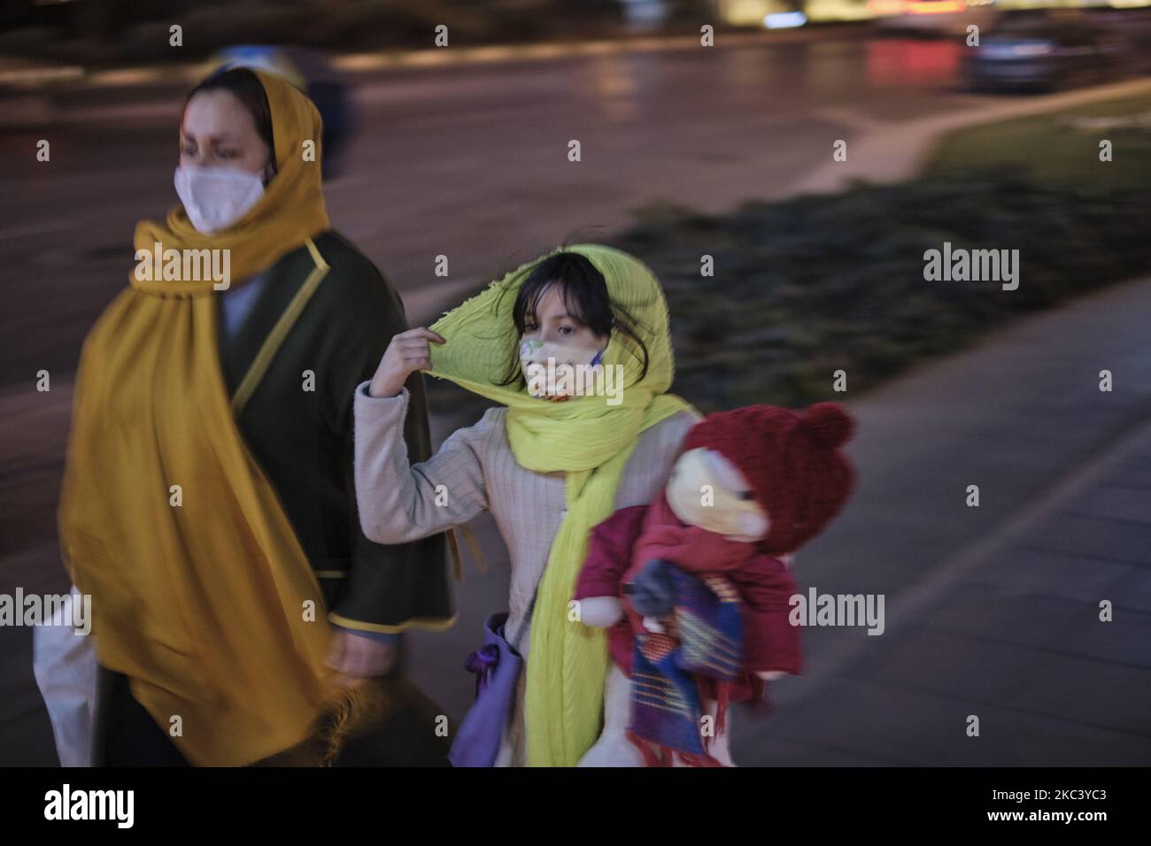 An Iranian young girl and her mother wearing protective face masks walk ...