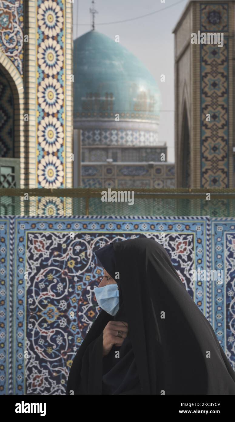 An Iranian veiled woman wearing a protective face mask walks along an ...