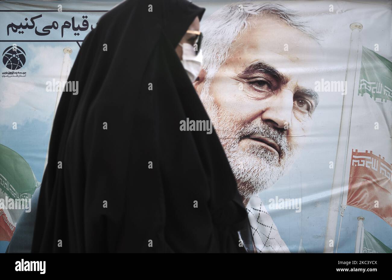 An Iranian veiled woman wearing a protective face mask walks past a ...