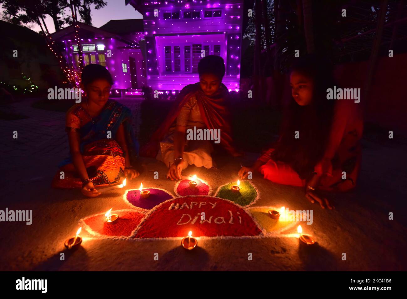 Girls pose after lighting oil lamps around a "Rangoli", a traditional ...
