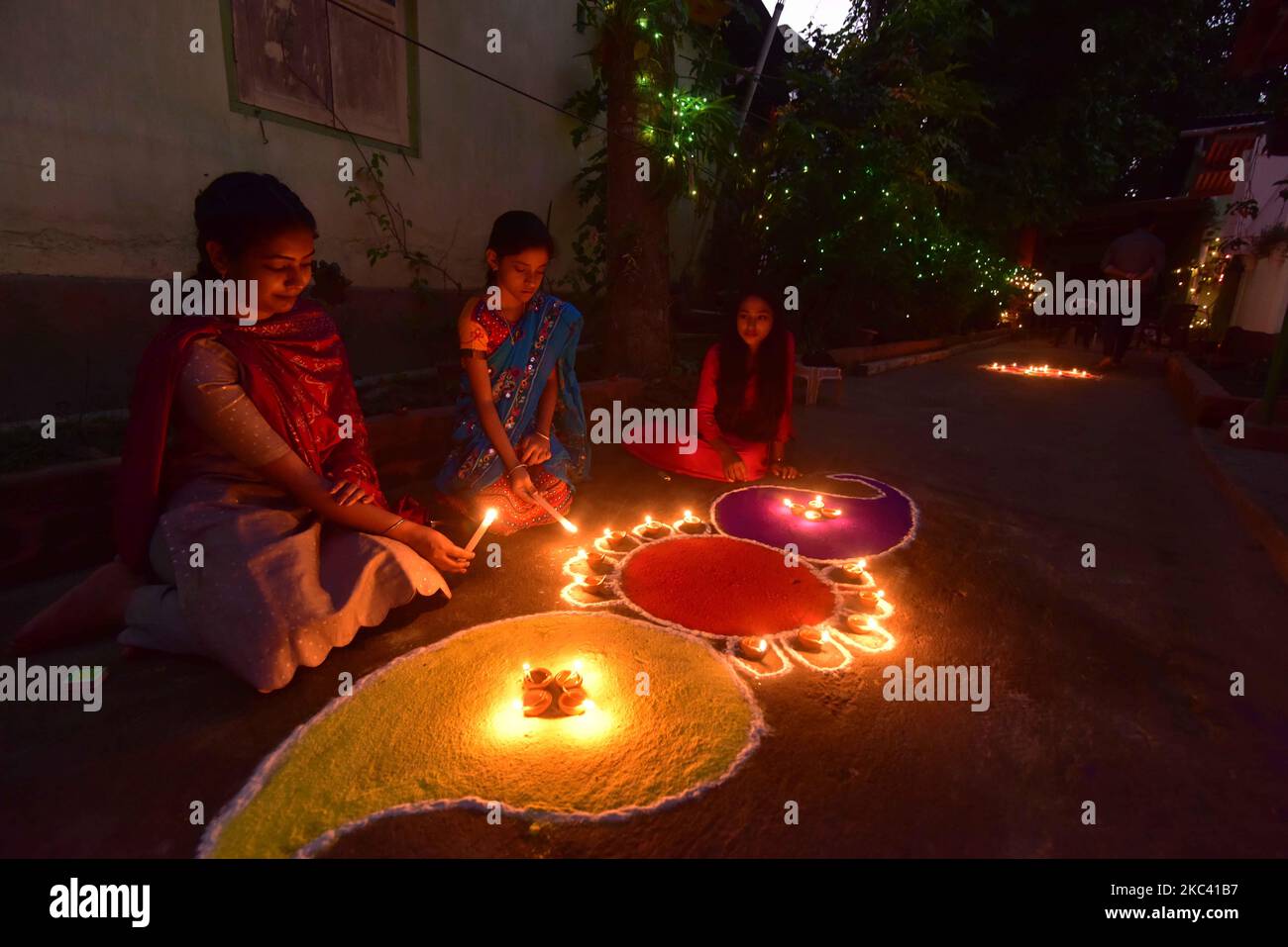 Girls pose after lighting oil lamps around a "Rangoli", a traditional ...