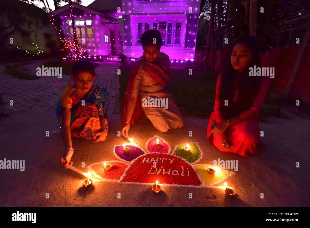Girls pose after lighting oil lamps around a "Rangoli", a traditional ...