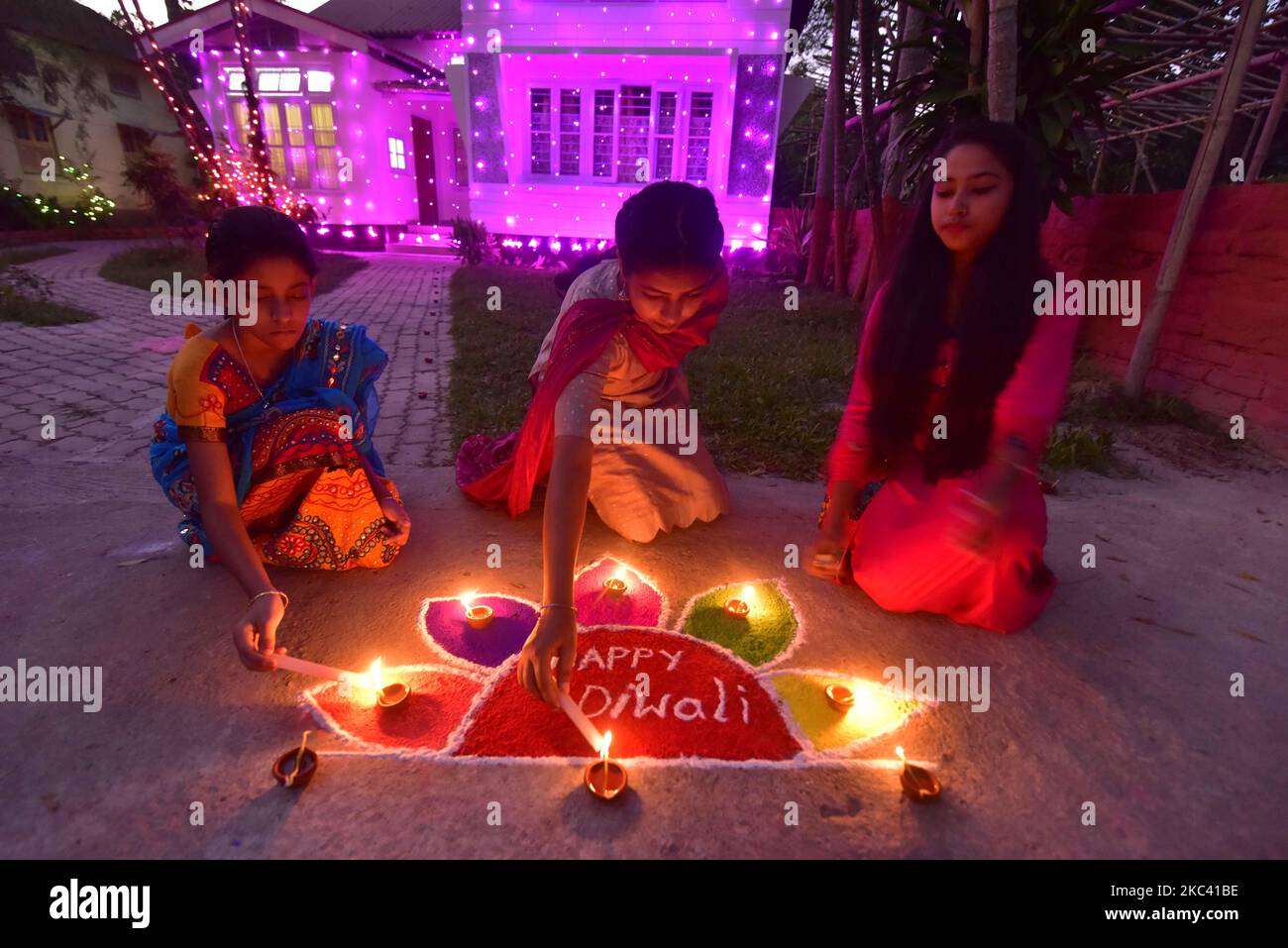 Girls pose after lighting oil lamps around a "Rangoli", a traditional ...