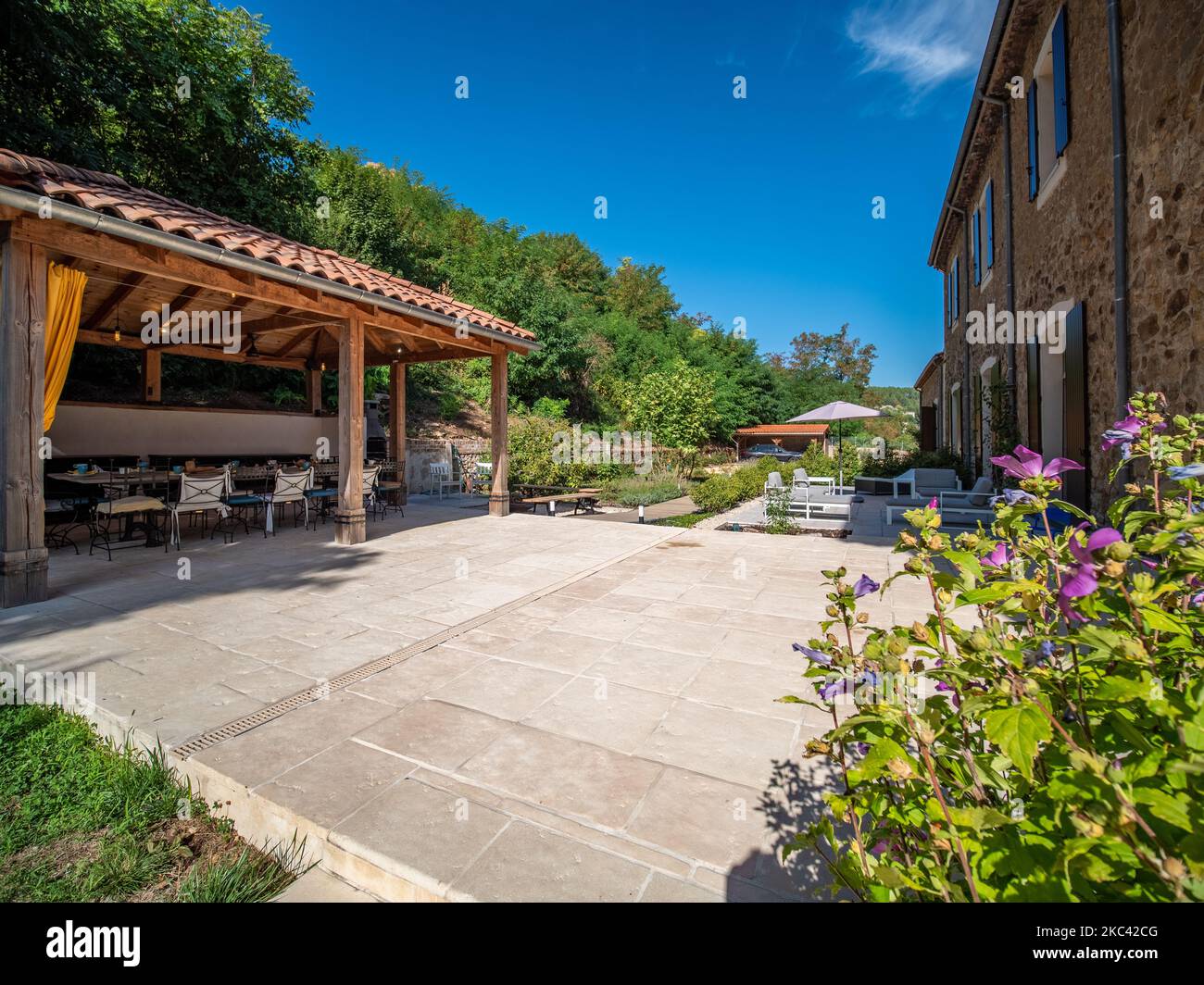 An exterior with a large stone terrace with wooden patio on the left ...