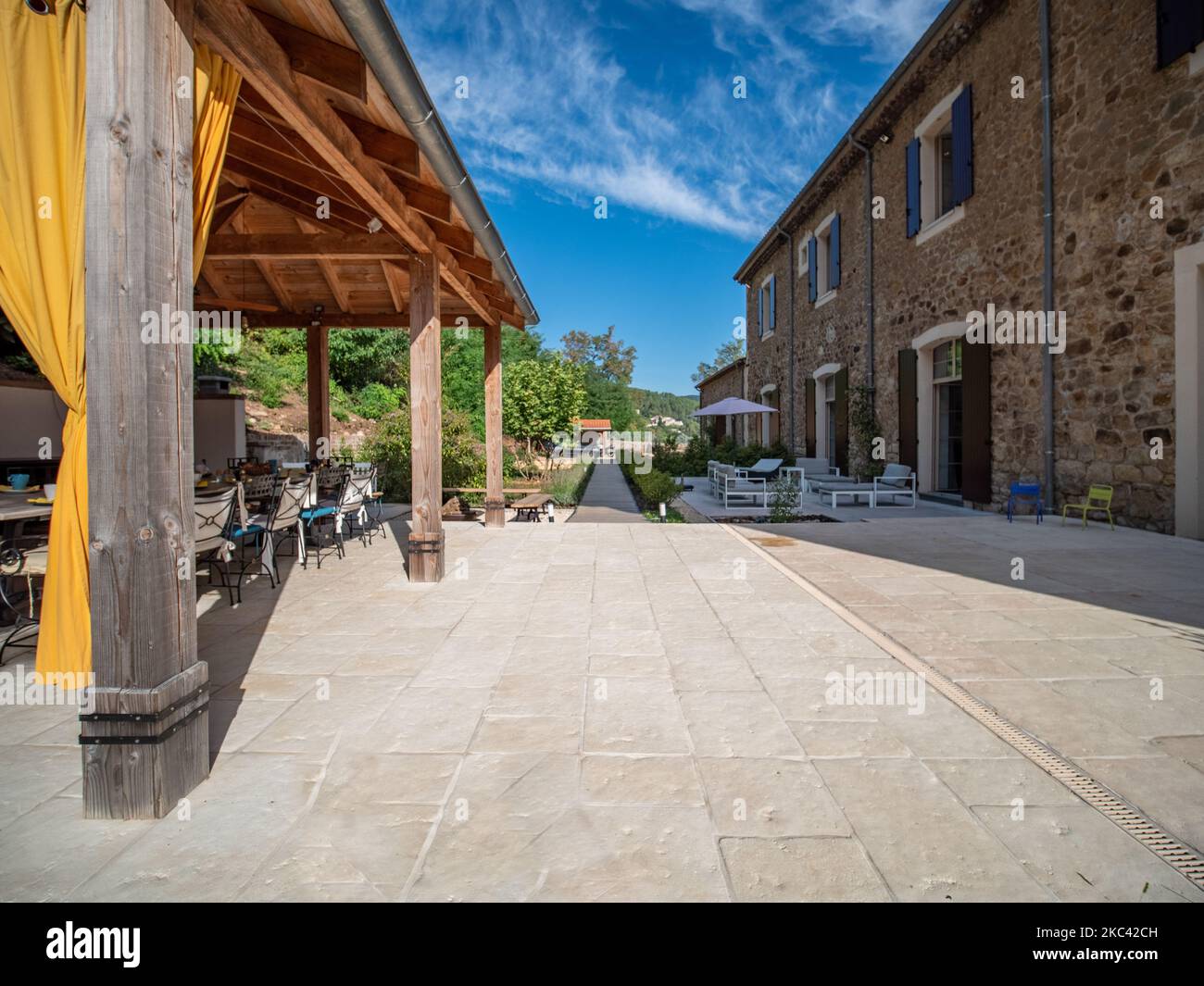 An exterior with a large stone terrace with wooden patio on the left ...