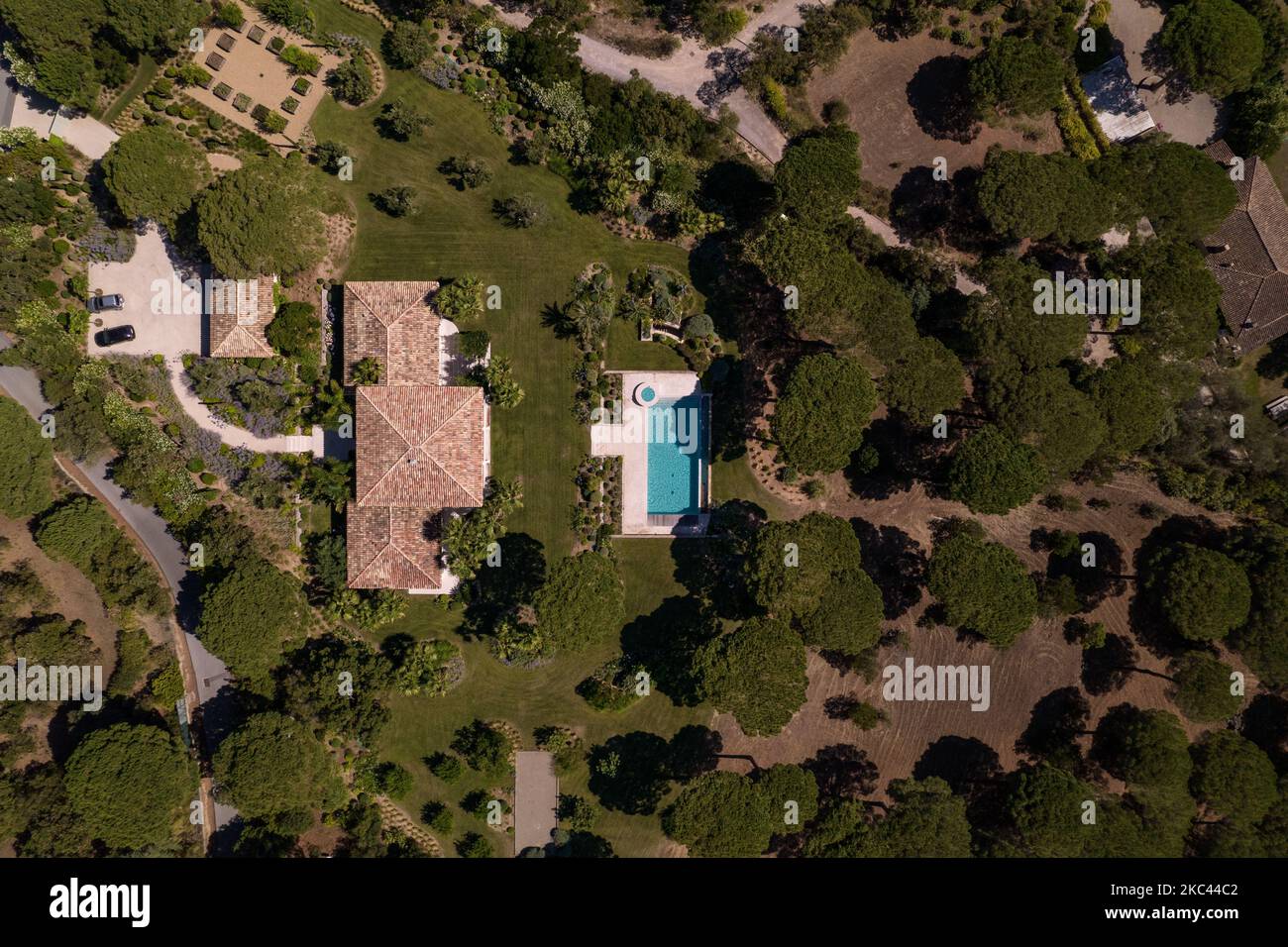 An aerial view of a large villa and a backyard with a pool surrounded ...