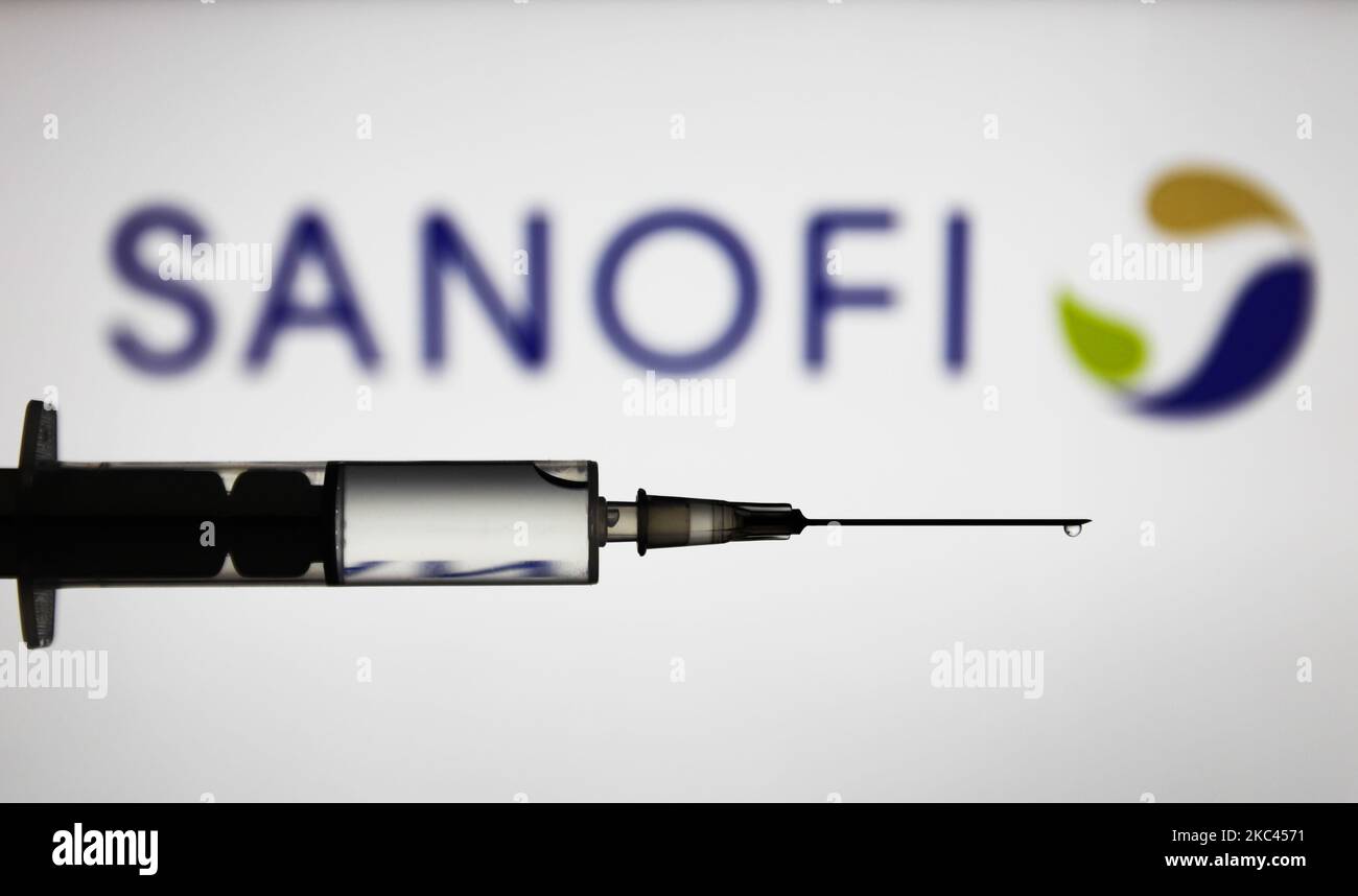 Medical syringe is seen with Sanofi company logo displayed on a screen ...