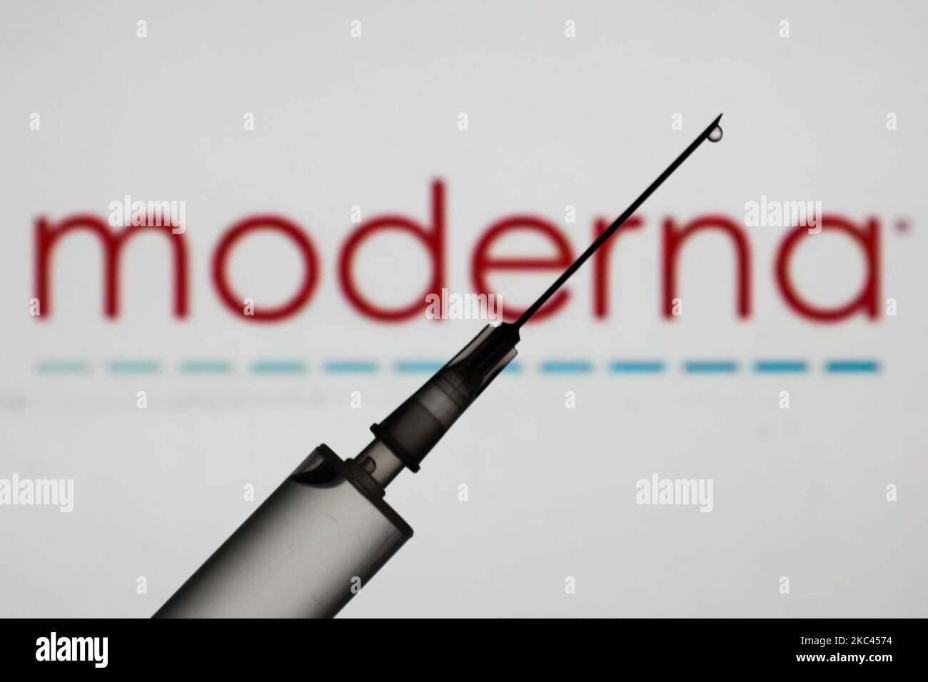 Medical syringe is seen with Moderna company logo displayed on a screen ...