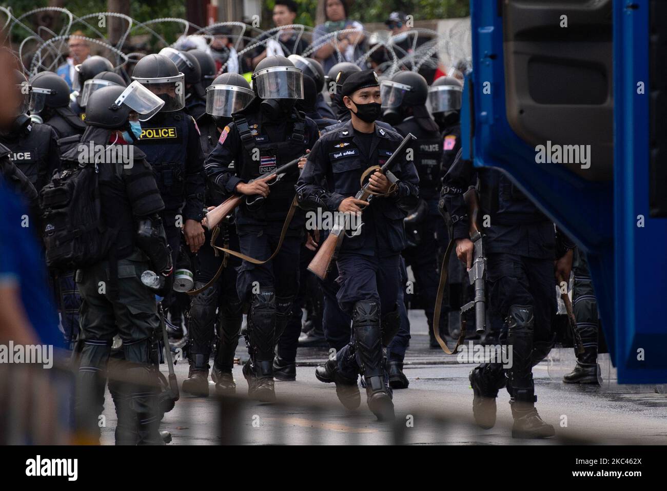 Riot police wear gas masks and anti-riot gear walk in formation during ...