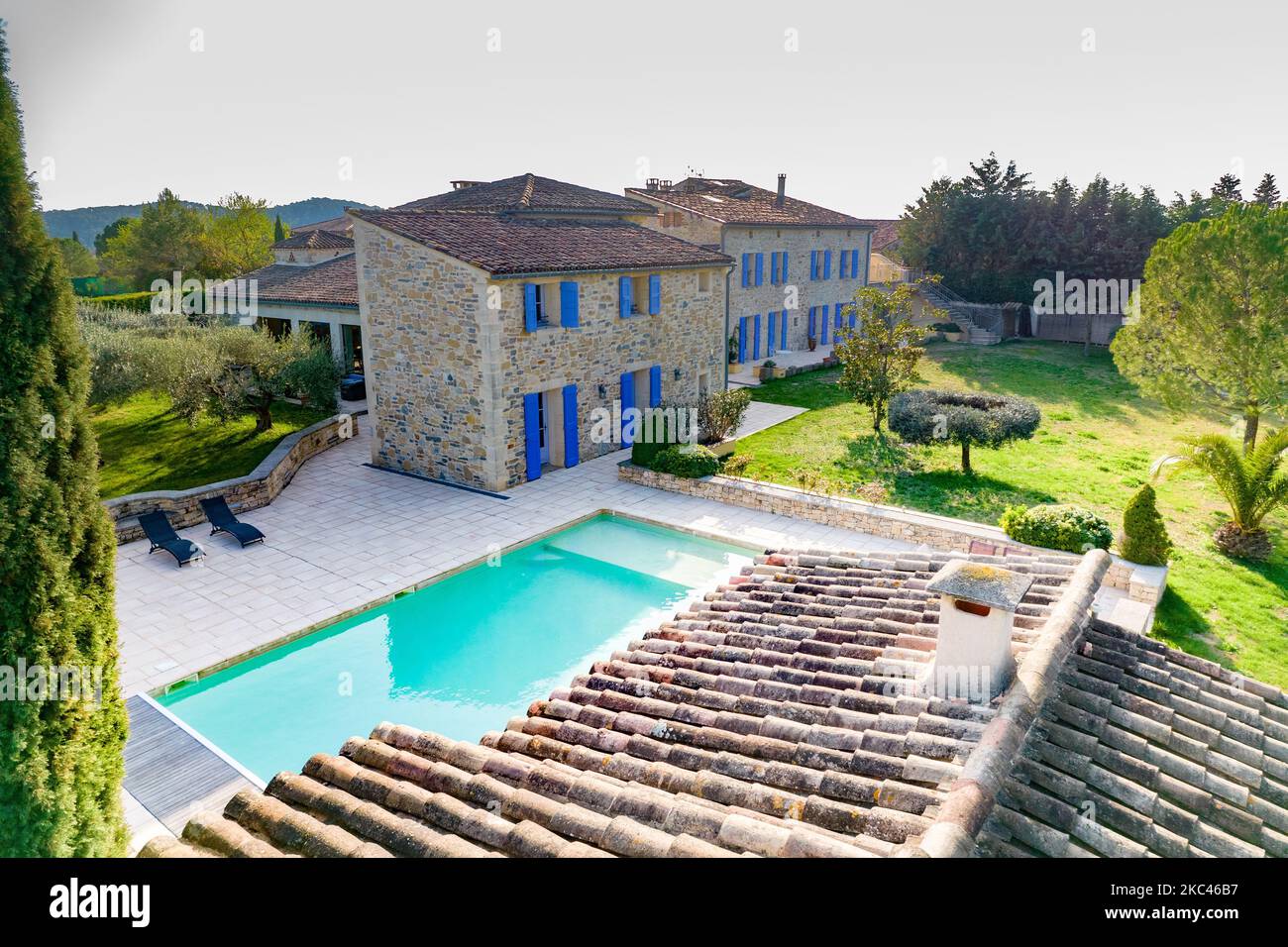 An aerial view of a large stone villa with a pool and vegetation on the ...