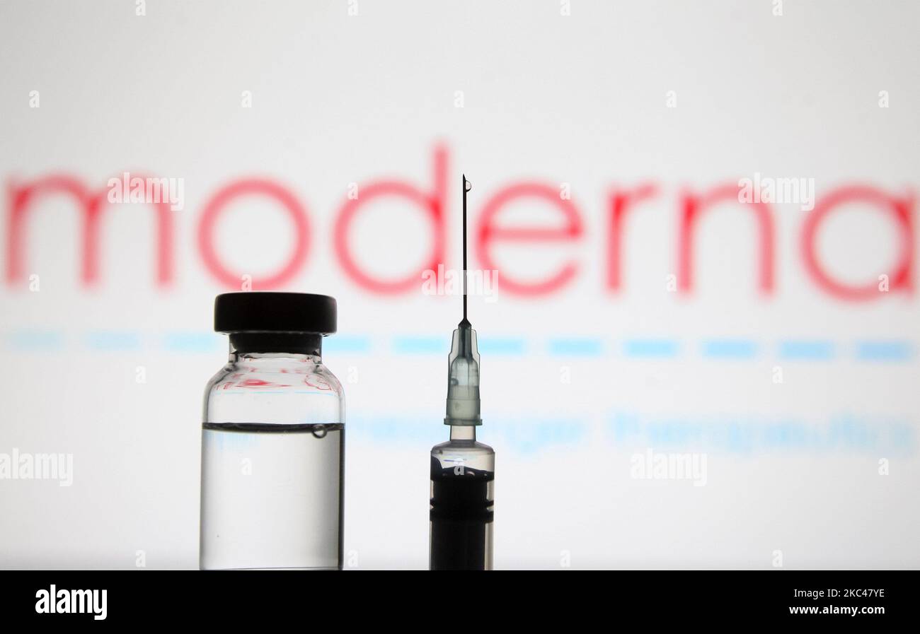 A medical syringe and a vial in front of the Moderna logo are seen in ...