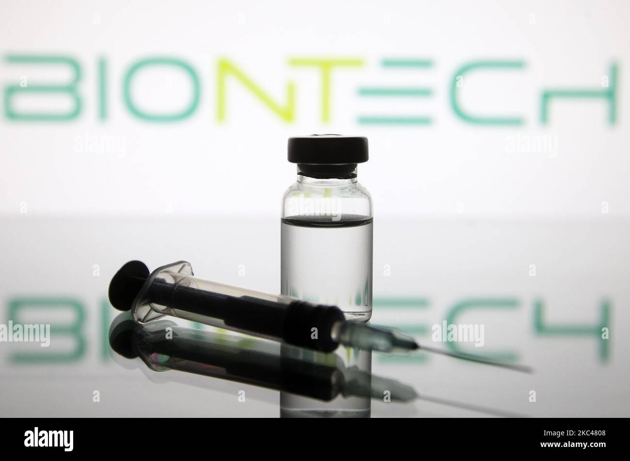 A medical syringe and a vial in front of the Biontech German ...