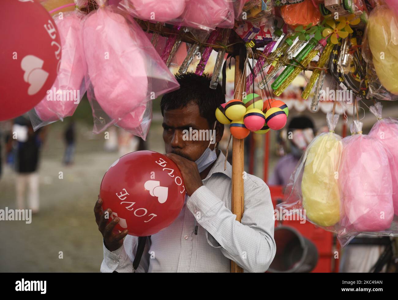 A vendor blowing a balloon to sell on the banks of Brahmaputra river on ...