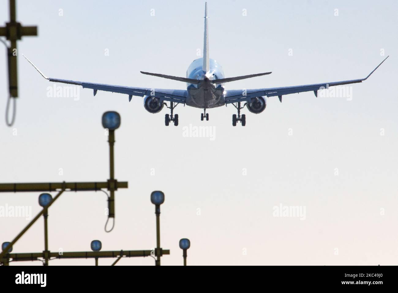 Rear view of various aircraft landing behind the runway lights in ...